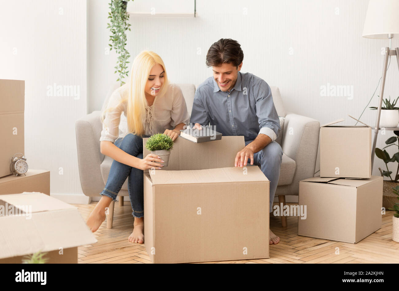 Young man and woman packing things in moving boxes indoor Stock Photo ...