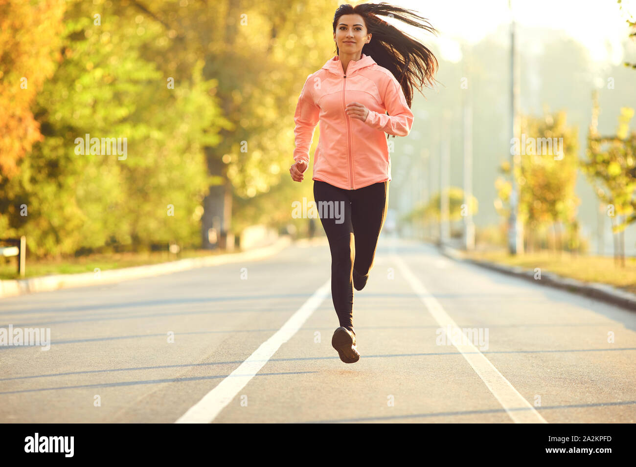 Brunette girl runs in the morning in a city park. Jogging for health ...