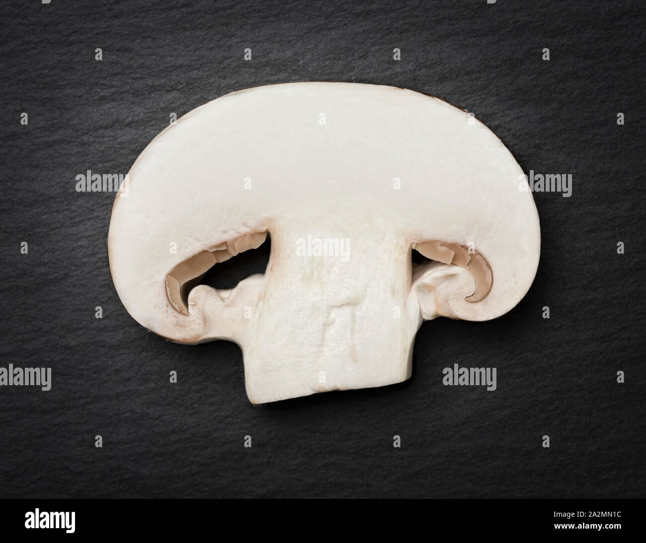 Cut champignon isolated on dark gray flagstone Stock Photo - Alamy