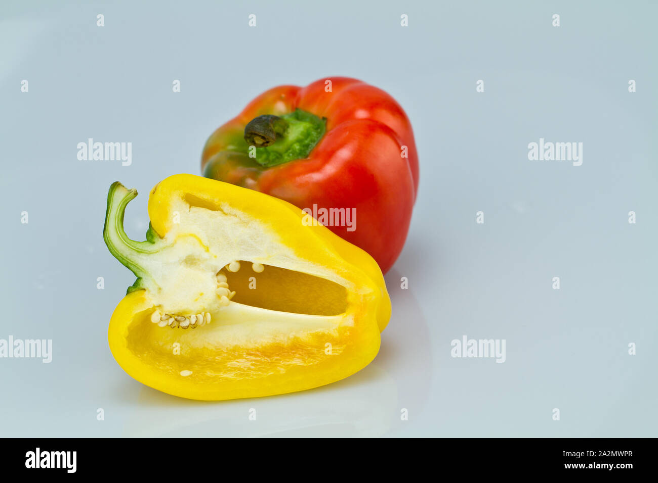 Green, red and yellow capsicums on white table with white background ...