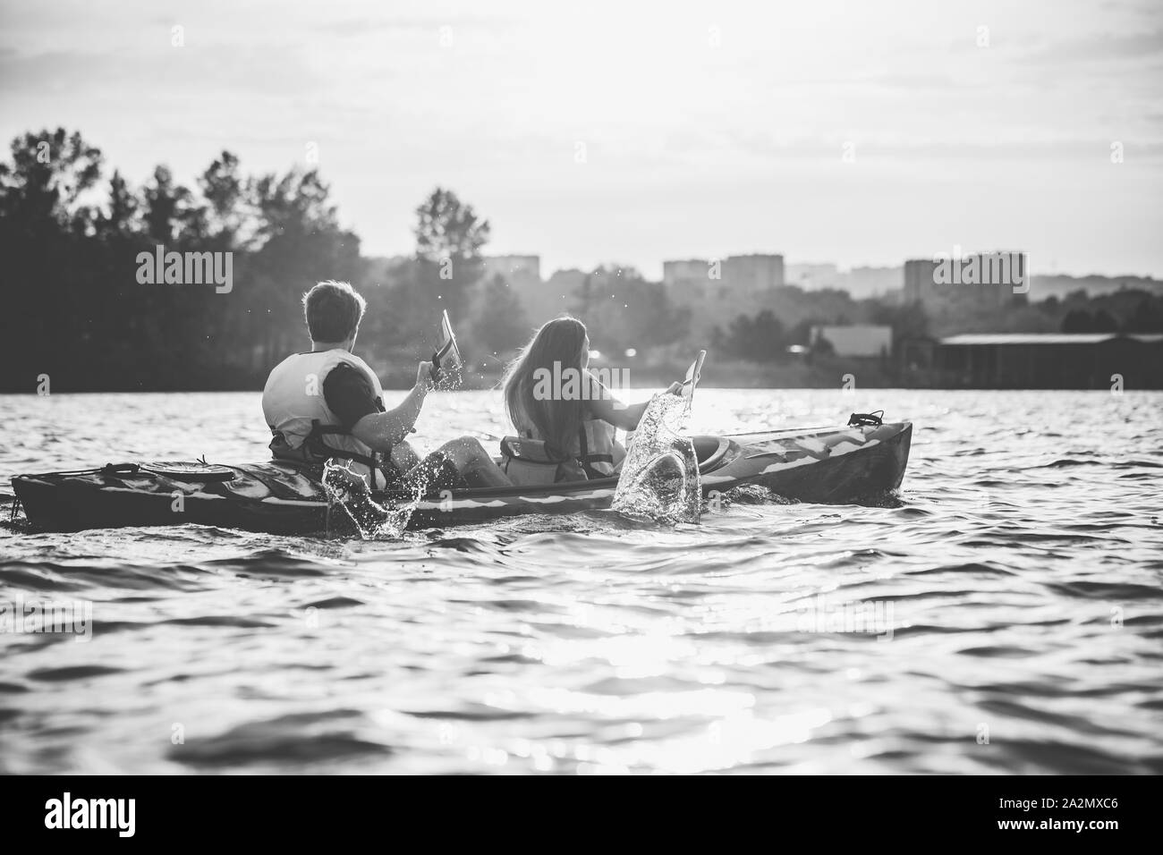 Happy young caucasian couple kayaking on river with sunset in the ...