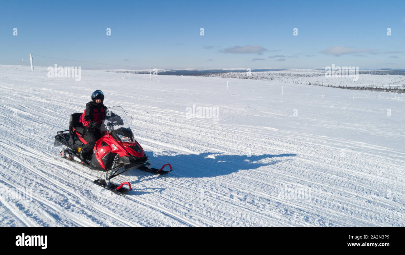 Aerial image of a woman driving snowmobile at winter wonderland Lapland ...
