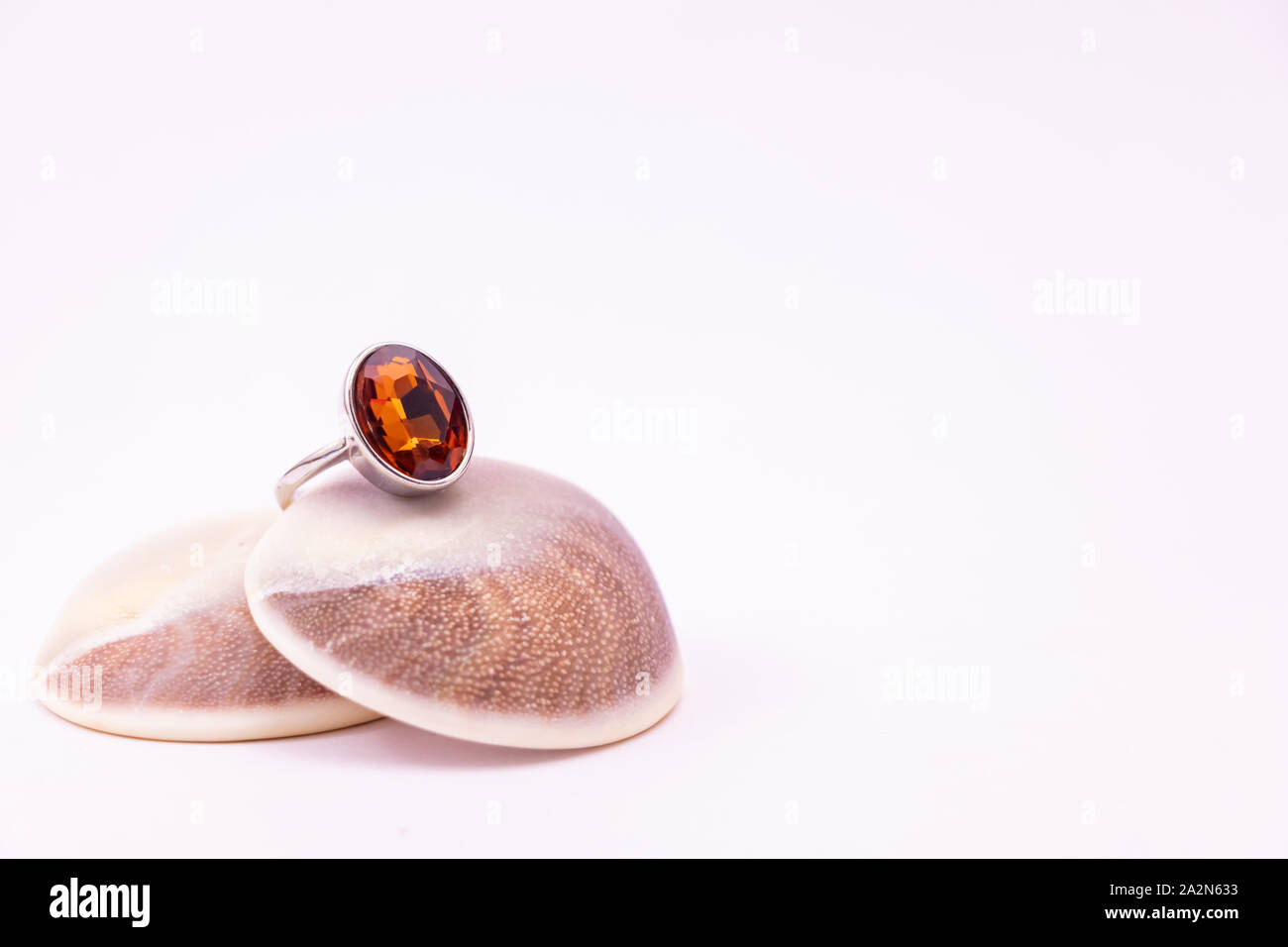 Gemstone ring concept. Cinnamon stone ring on seashell with white ...