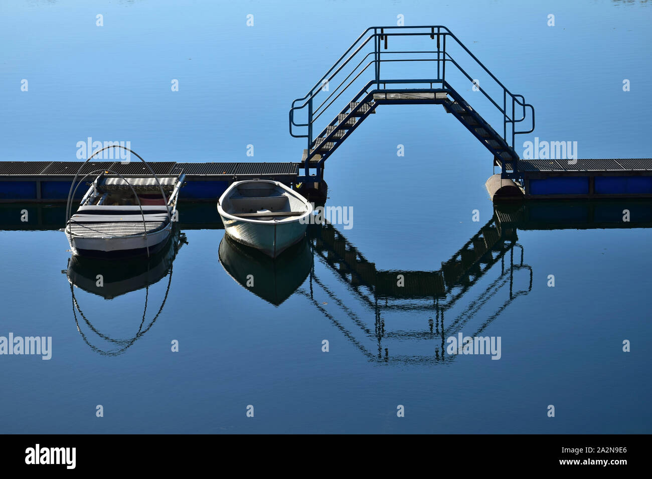A lake, a boat bridge with a crossover and two boats. The scene is ...