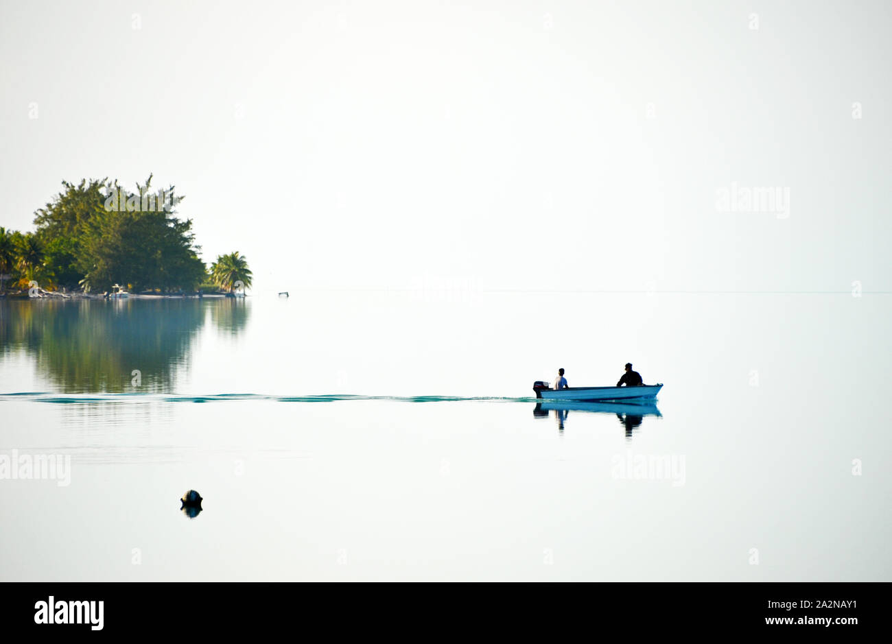 A small fishing boat sets out across the lagoon from the village of ...
