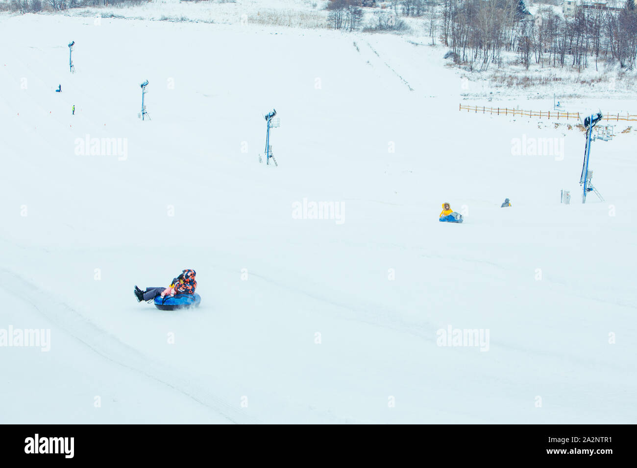 sliding down by snowed hill on inflatable tubes. winter fun activities ...