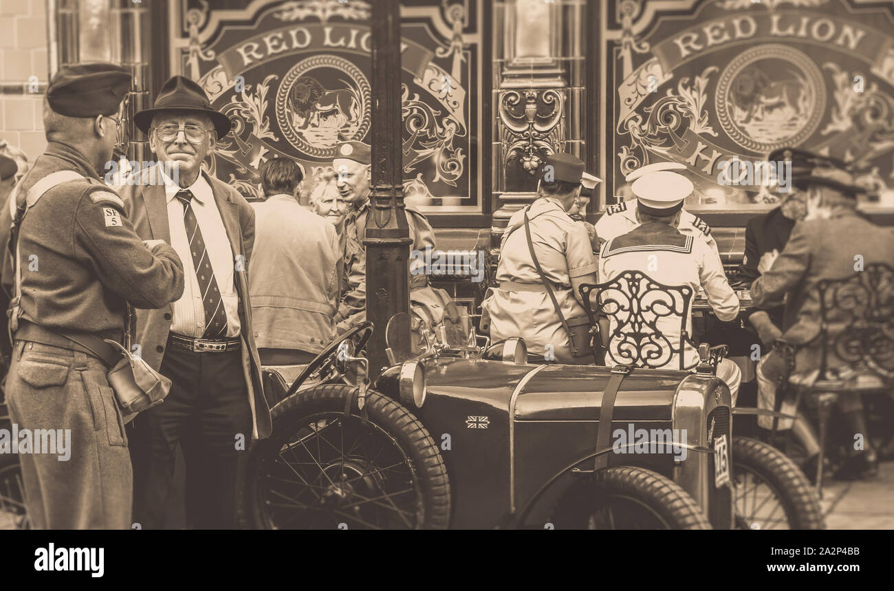 Sepia WWII street scene, UK forties re-enactors chatting outside ...