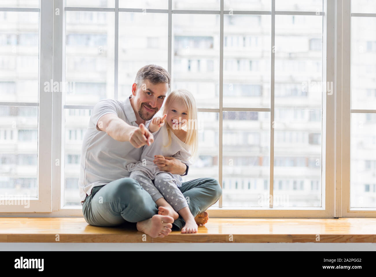 Happy father with daughter pointing with fingers against of window ...