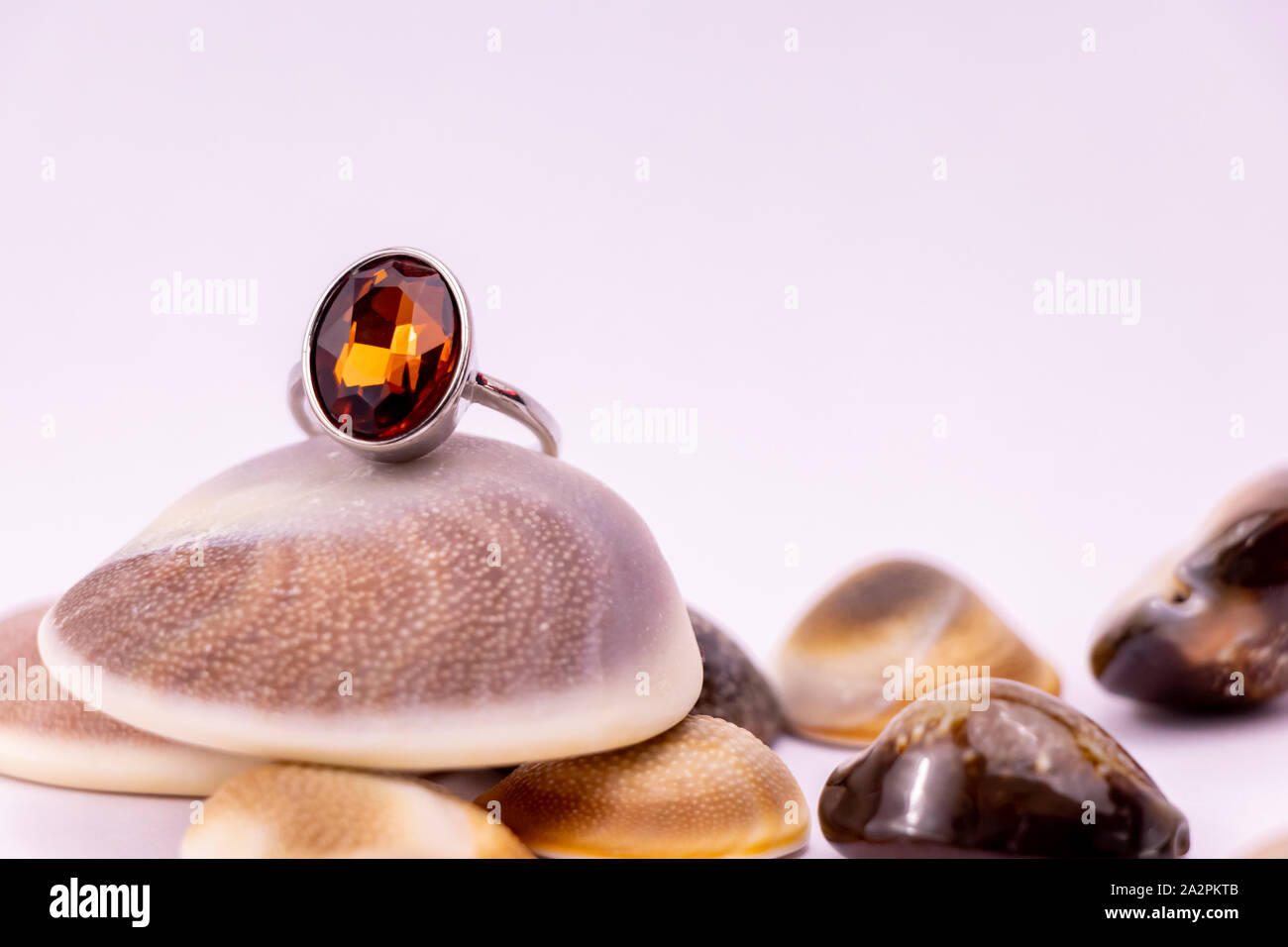 Gemstone ring gift concept. A cinnamon stone ring on seashell on white ...
