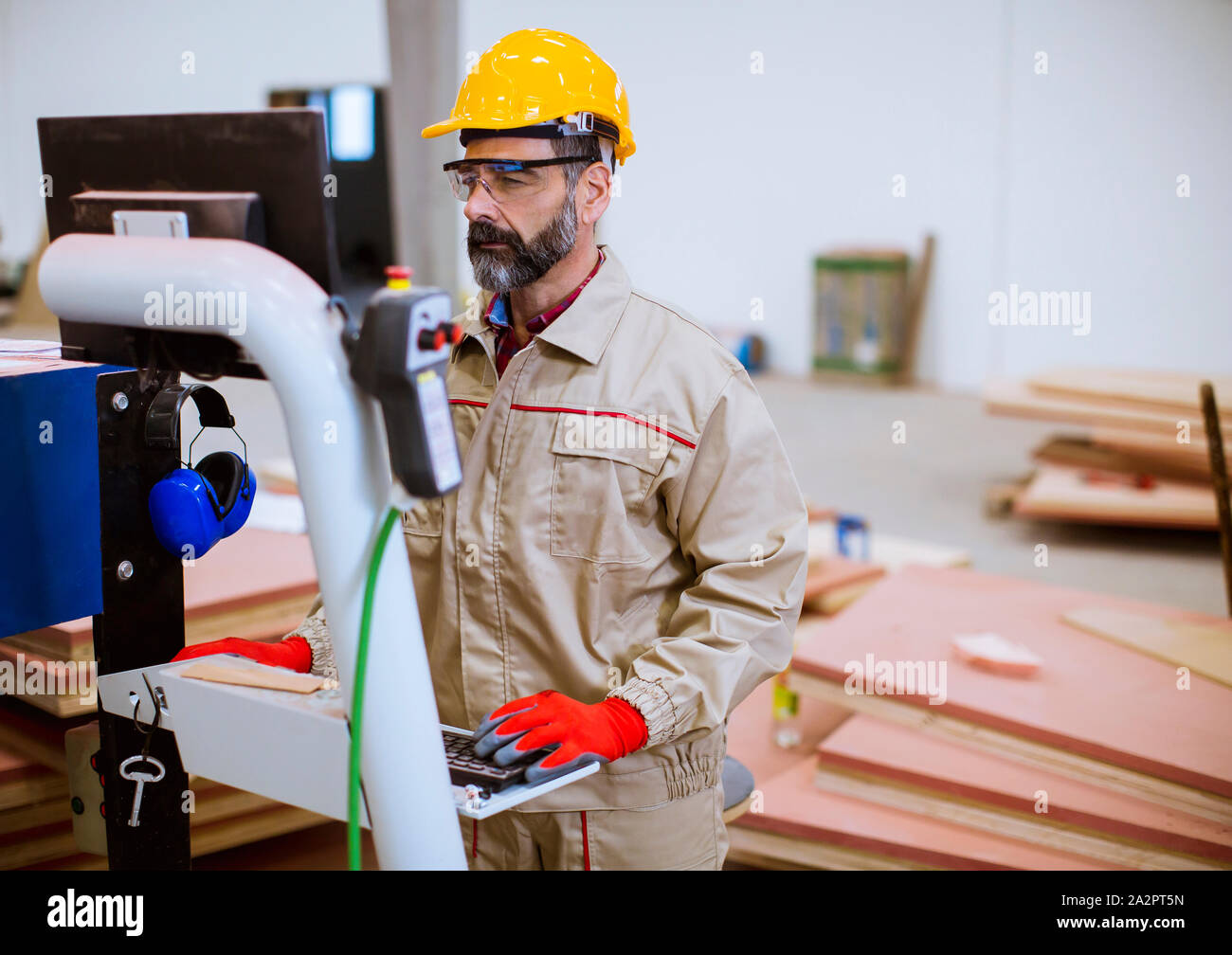 Portrait of senior man operating machine units in modern wooden factory ...