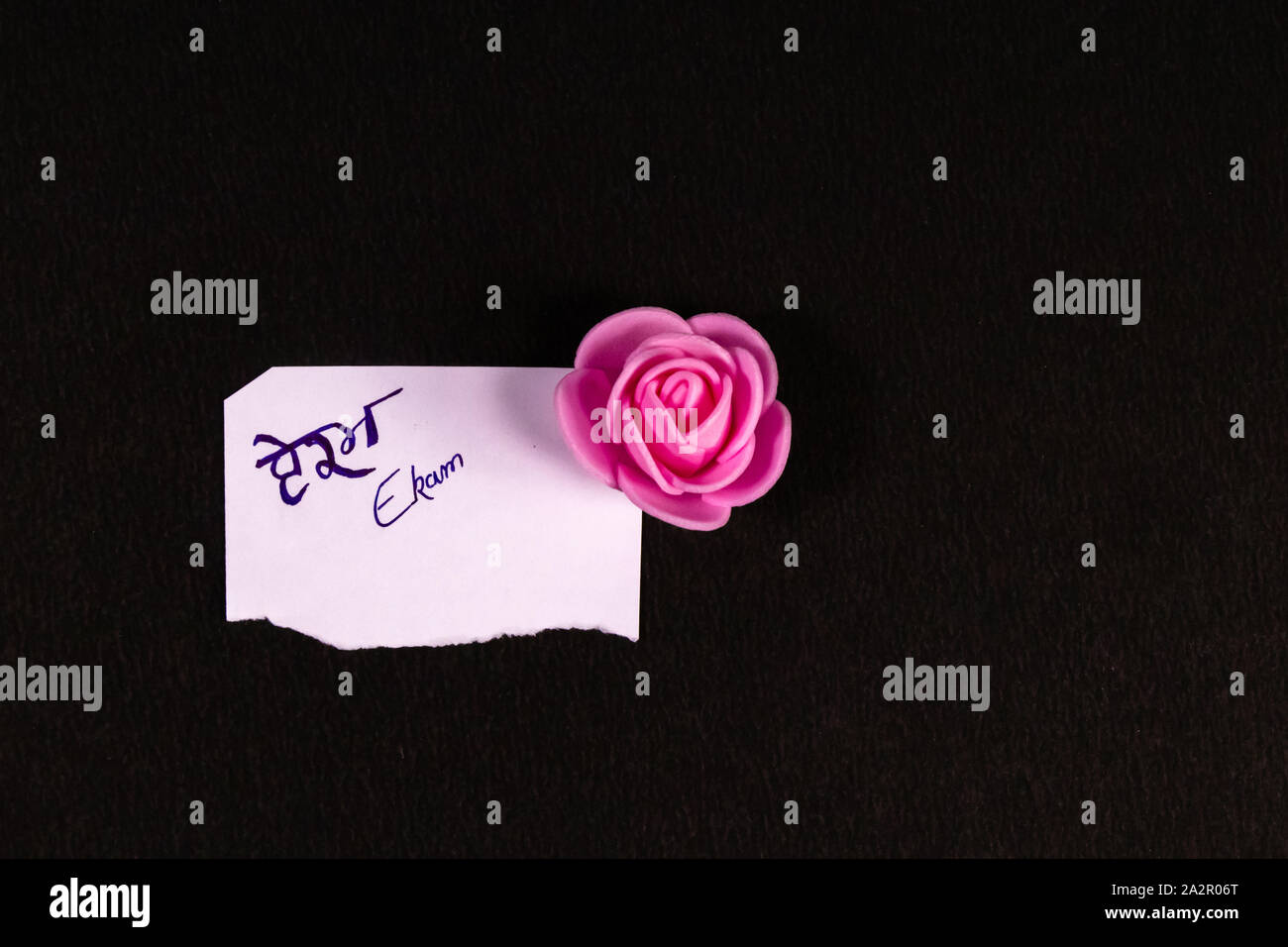 Hand written initials on white paper with beautiful artifical pink rose ...