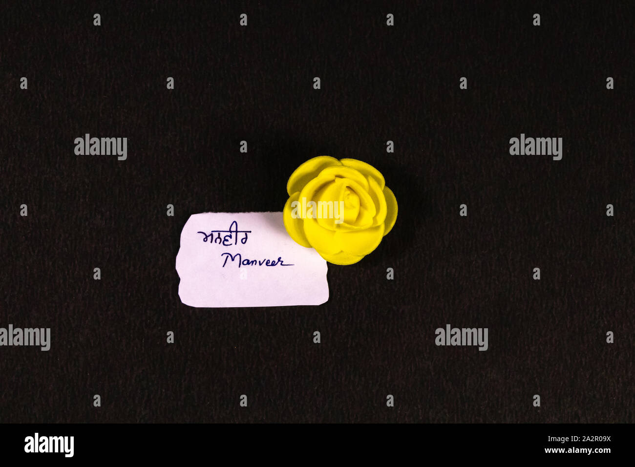 Hand written initials on white paper with beautiful artifical rose ...