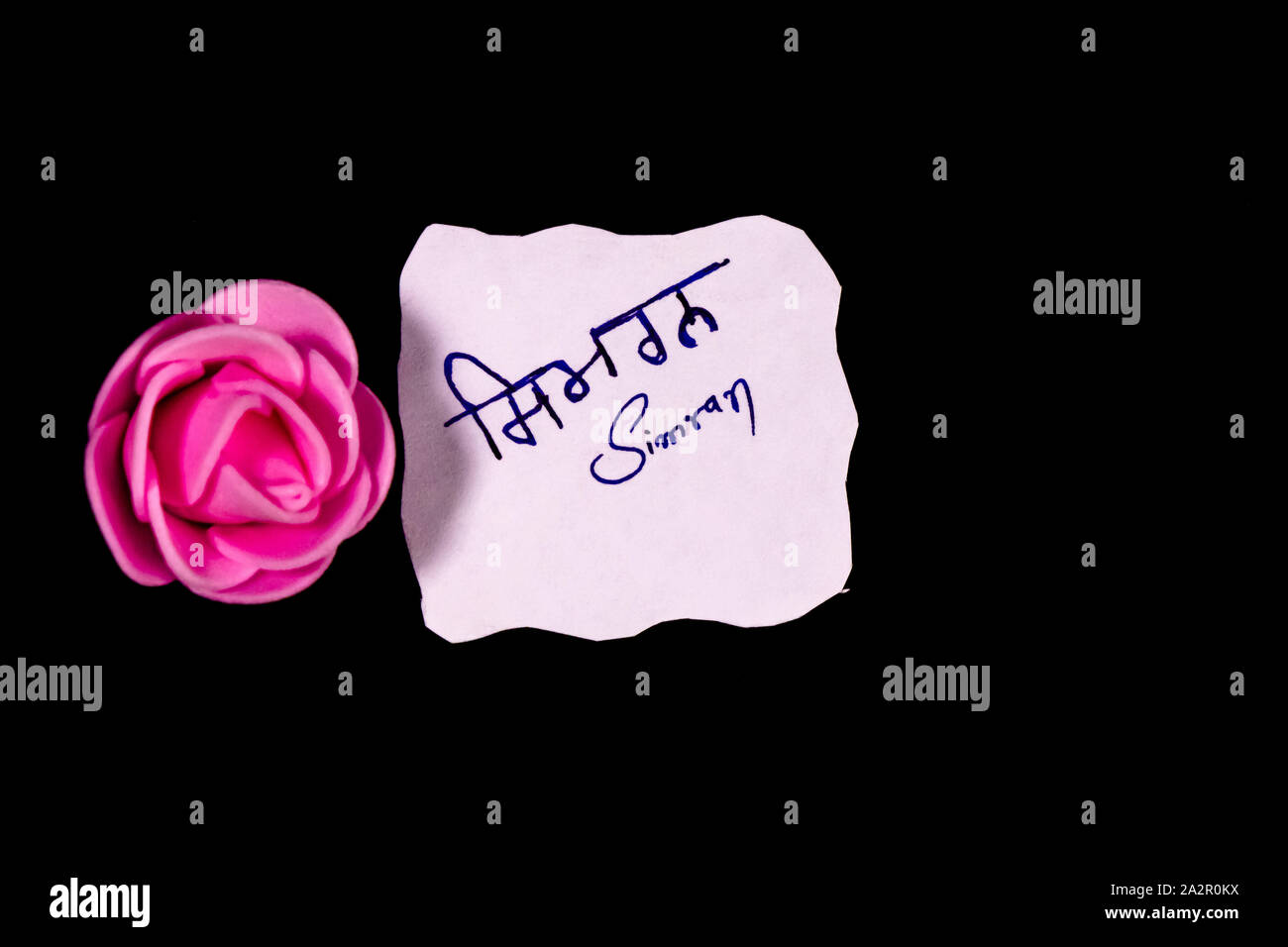 Hand written name initials on white paper with beautiful artifical pink ...