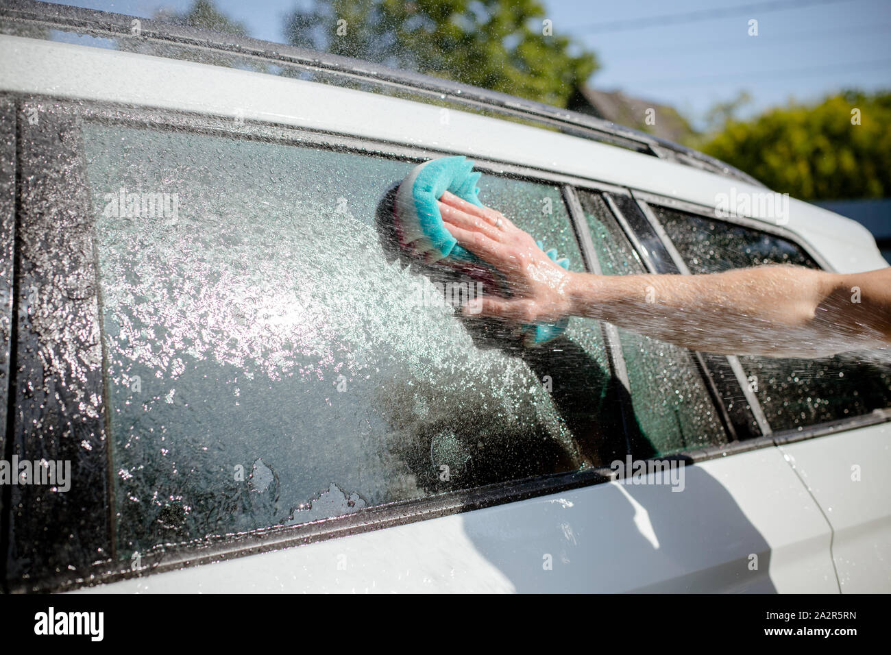 man washing a soapy blue car with a pink sponge Stock Photo - Alamy
