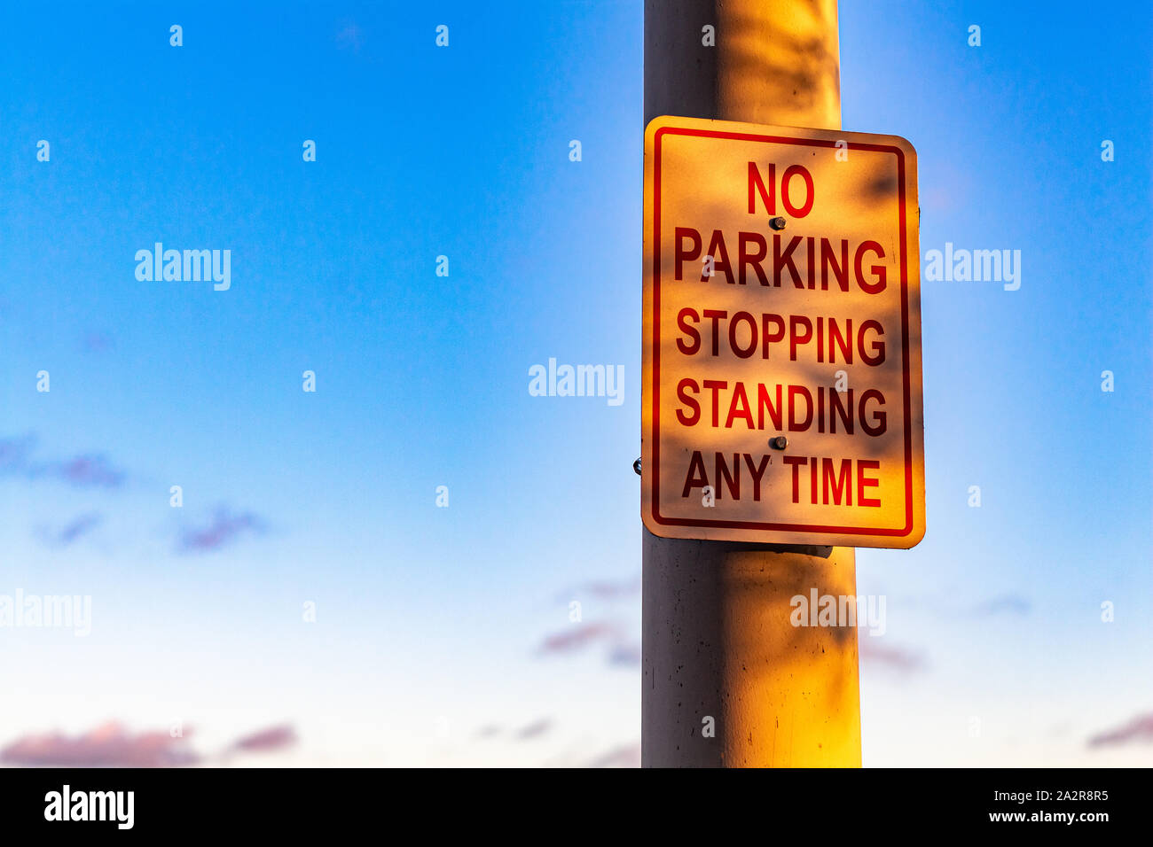A sign on a concrete pole informs motorists: No Parking, No Stopping ...