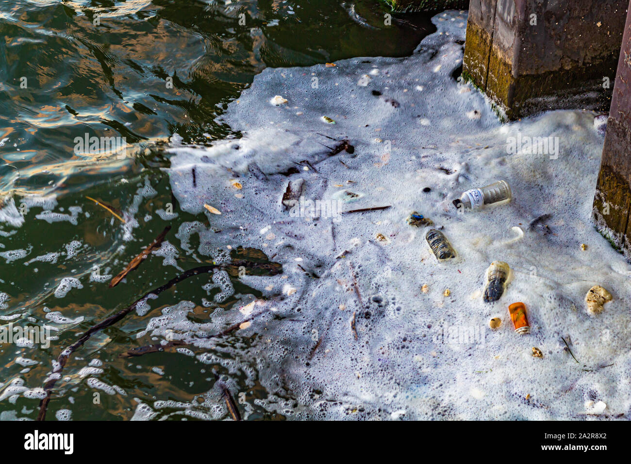 Garbage floats in foamy water by a pier Stock Photo - Alamy