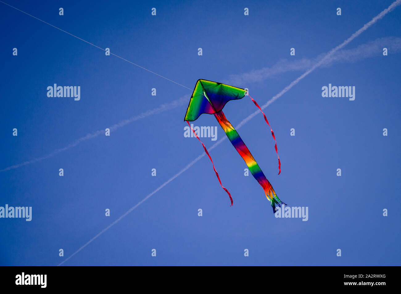 colorful kite flying high in blue sky Stock Photo - Alamy