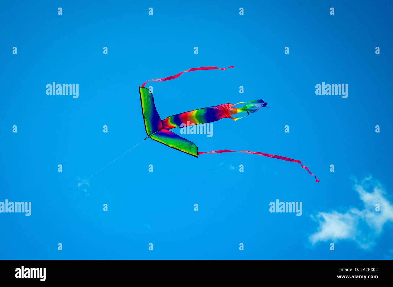 colorful kite flying high in blue sky Stock Photo - Alamy