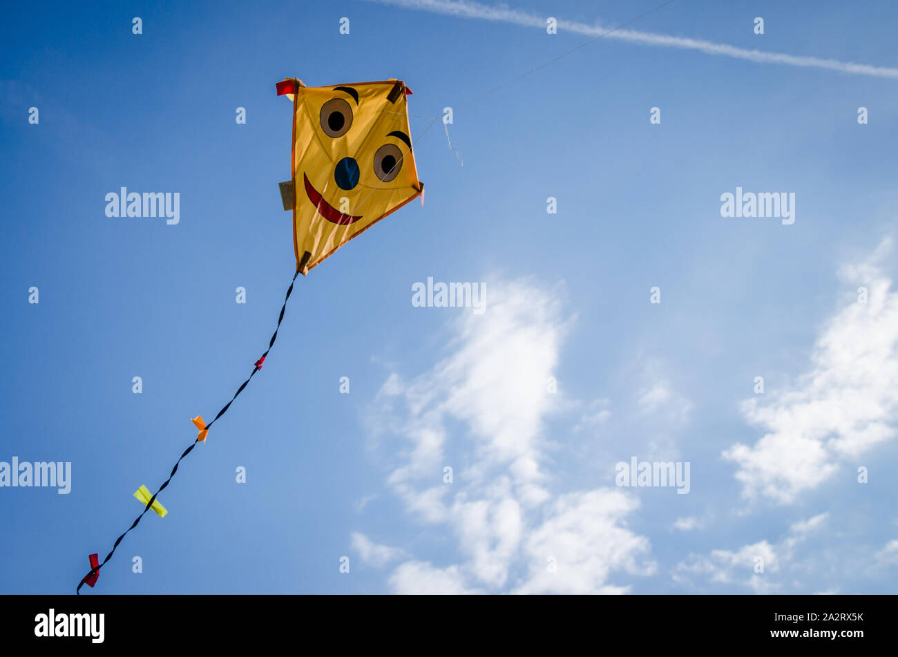 colorful happy smiling kite flying high in blue sky Stock Photo - Alamy