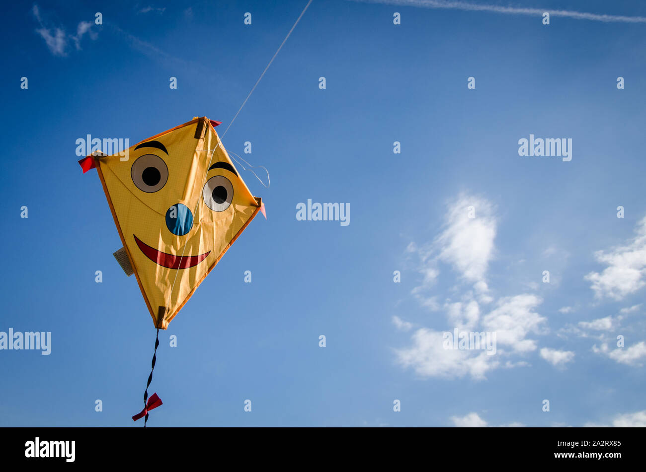 colorful happy smiling kite flying high in blue sky Stock Photo - Alamy