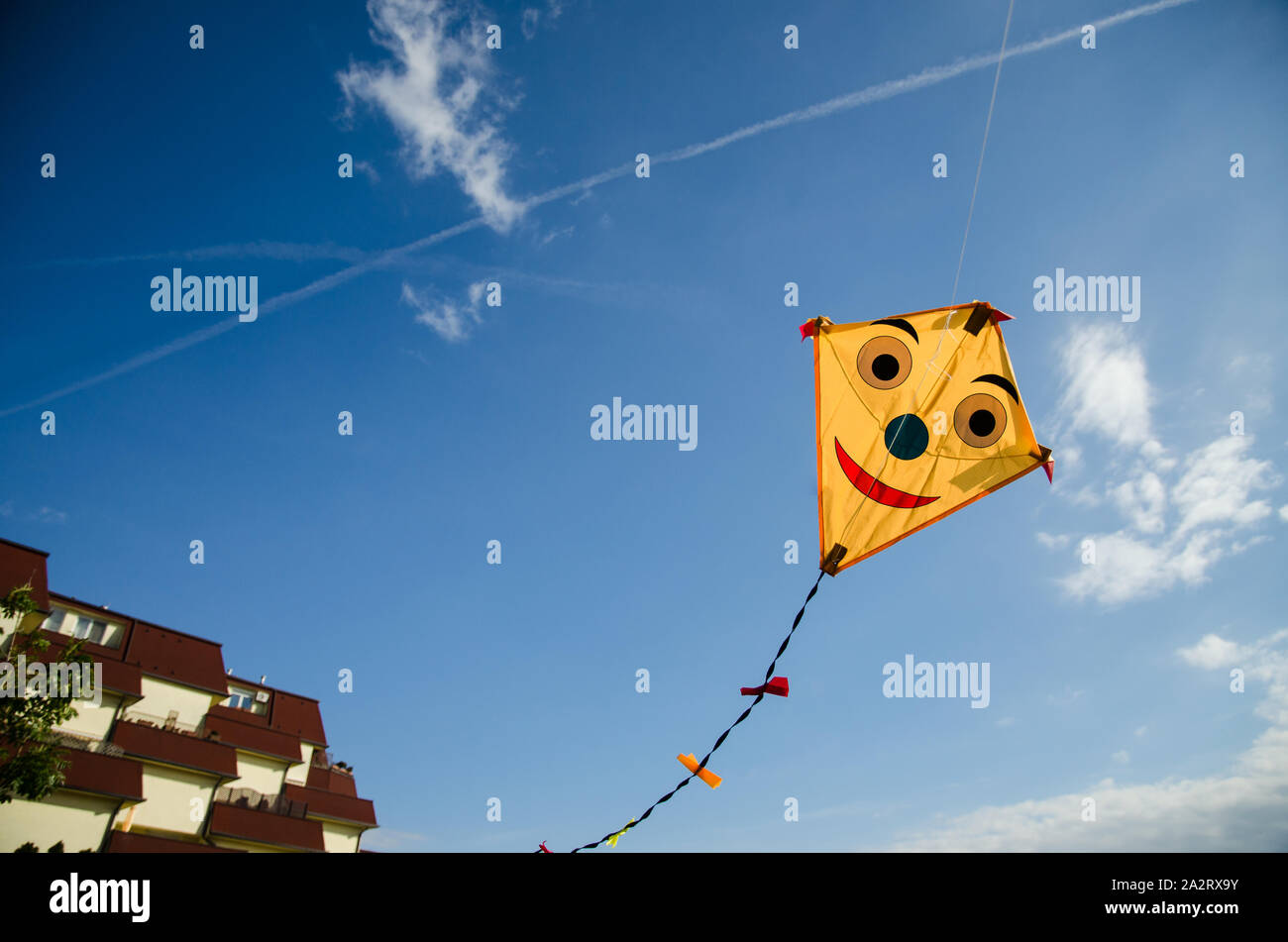 colorful happy smiling kite flying high in blue sky Stock Photo - Alamy