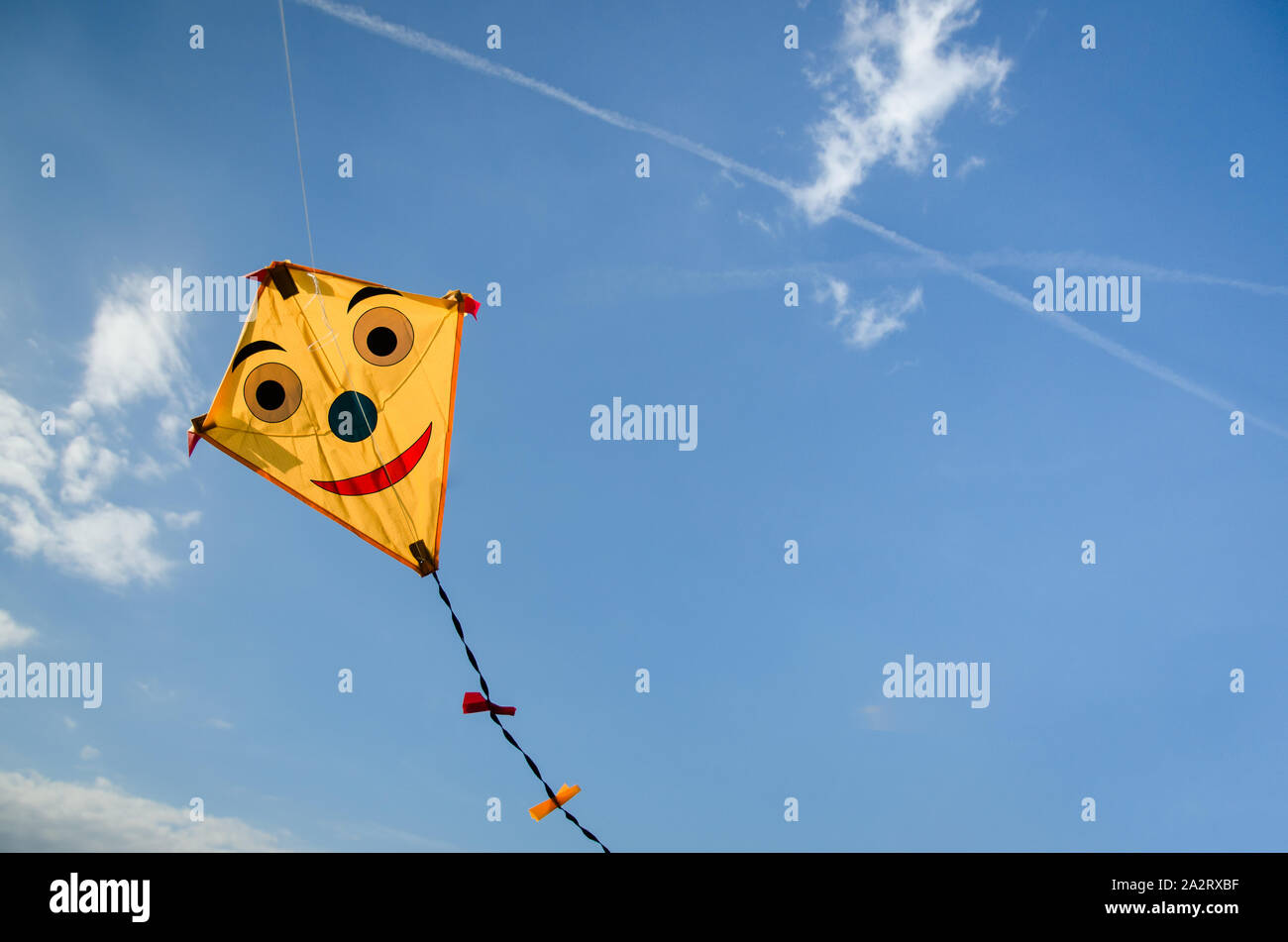 colorful happy smiling yellow kite flying high in blue sky Stock Photo ...