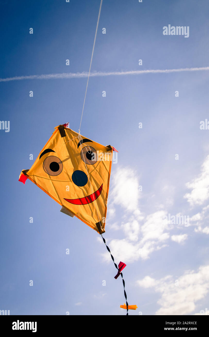 colorful happy smiling kite flying high in blue sky Stock Photo - Alamy