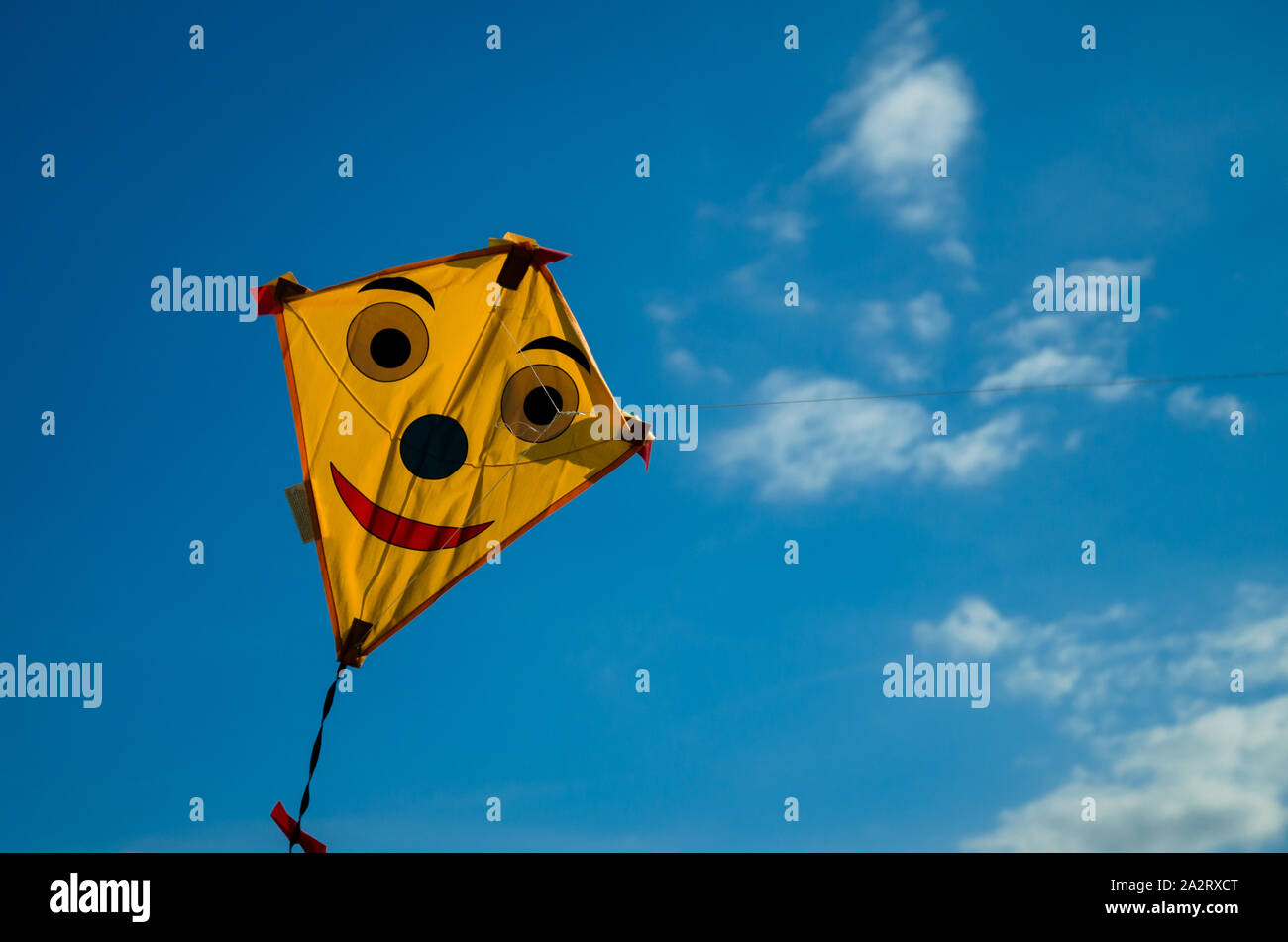 colorful happy smiling kite flying high in blue sky Stock Photo - Alamy