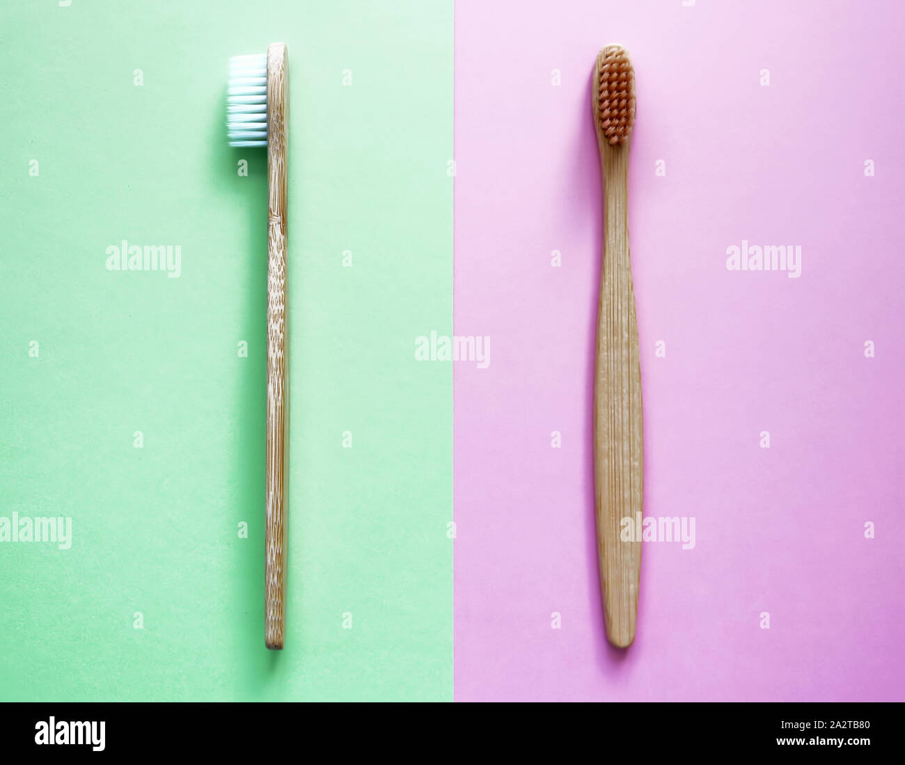 Bamboo toothbrushes on two colored background in trendy green and pink ...
