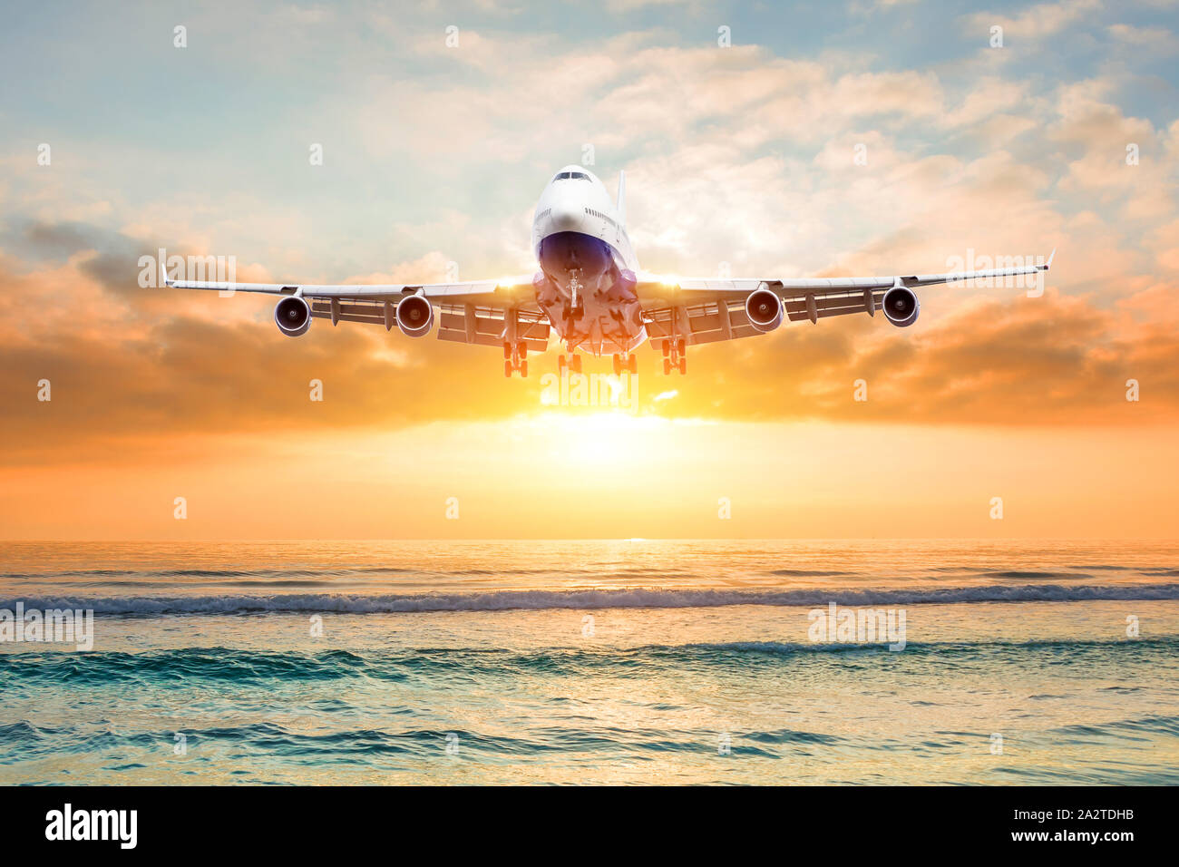 Airplane flies over the ocean during landing at sunset Stock Photo - Alamy
