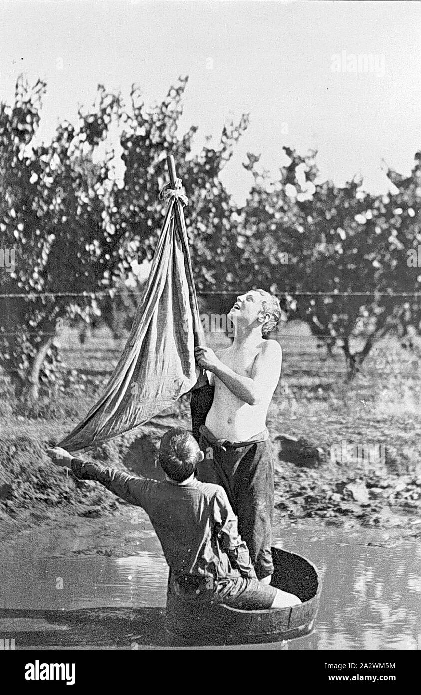 Negative - Two Boys arranging a Sail on a Water Barrel in a Waterhole ...