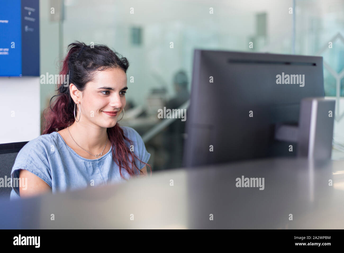 Young woman smiling watching messages on computer screen, in a ...