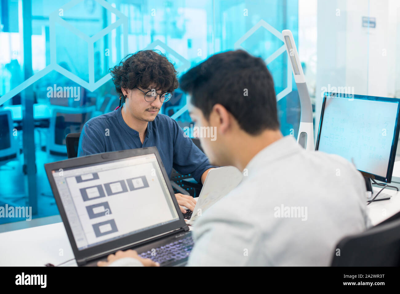 Two young men working at the computer in coworking office Stock Photo ...