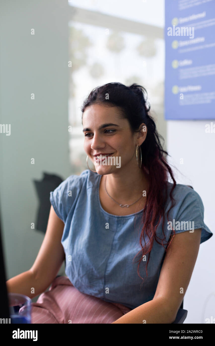 Young secretary smiling when viewing messages on the computer screen ...