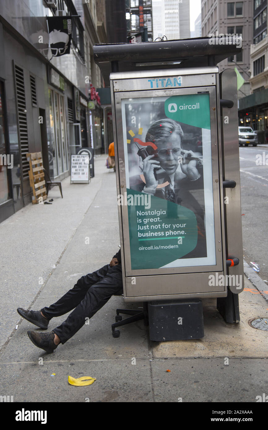 Man uses a phone booth in midtown Manhattan to take a snooze. New York ...