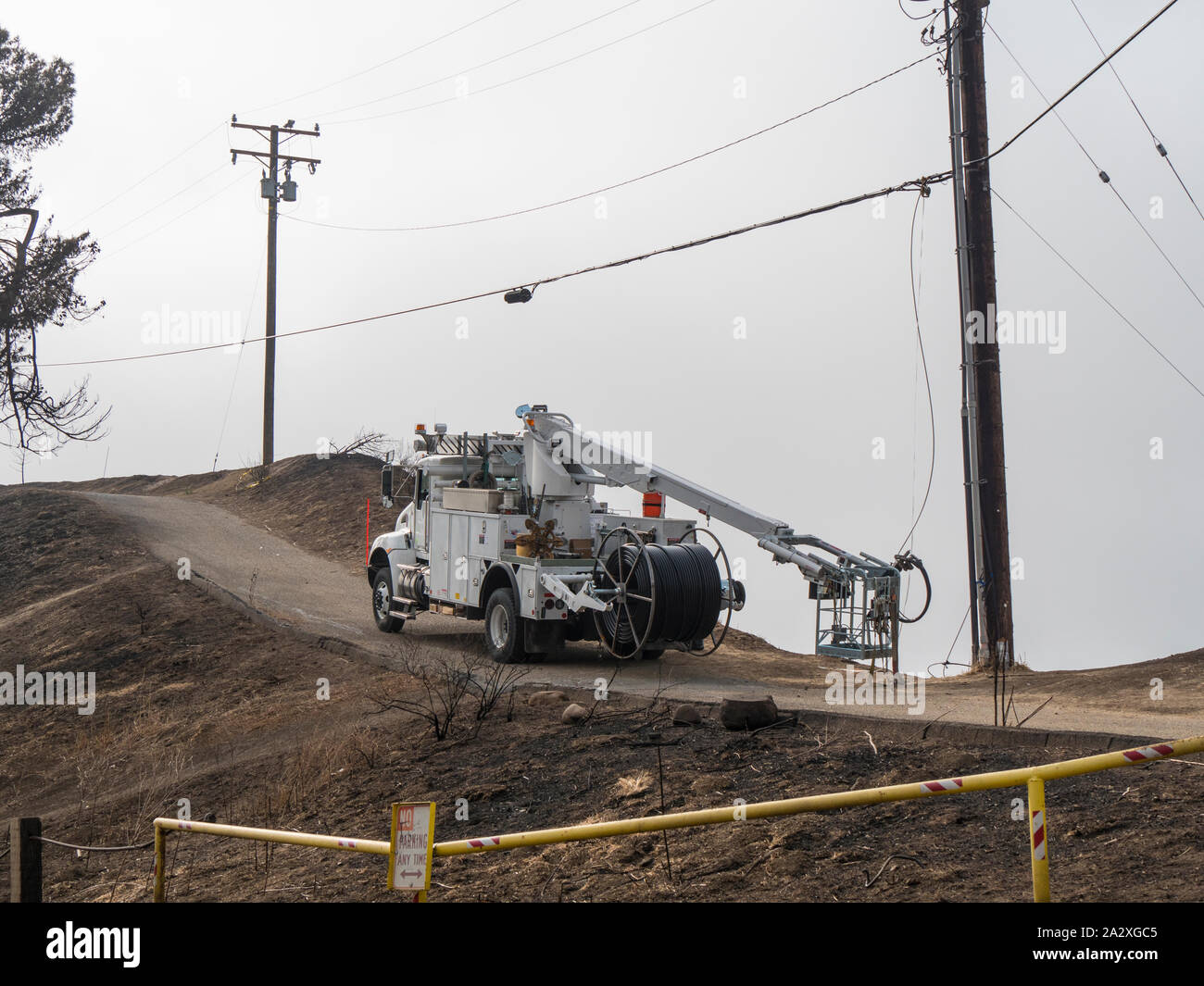 A white commercial truck parked while crew repairs down telephone line ...