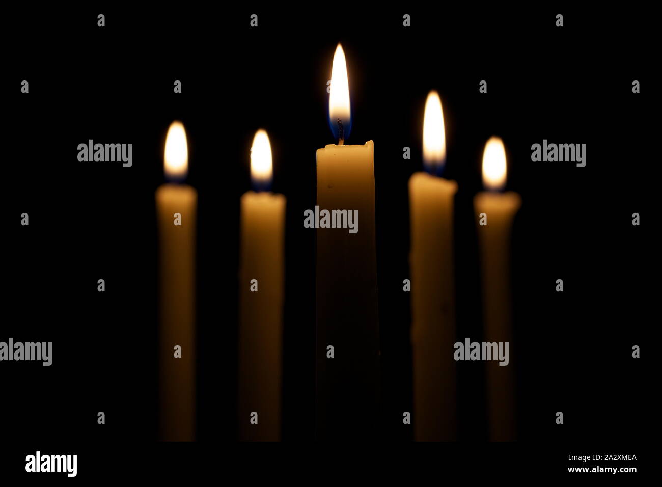 Five lit candles in the darkness Stock Photo - Alamy