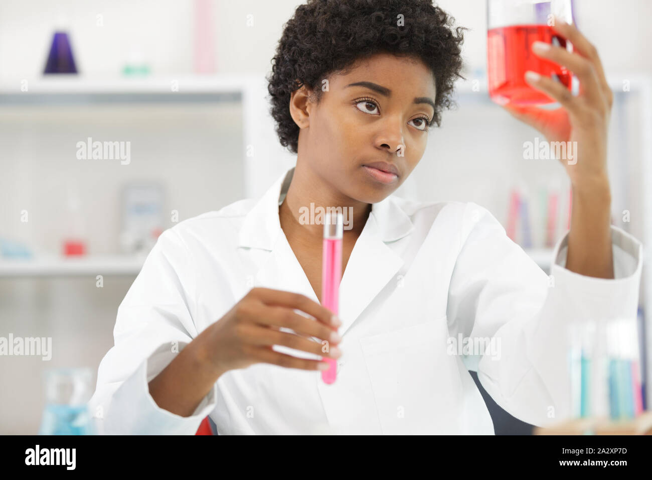 female scientist holding up a beaker to examine the liquid Stock Photo ...