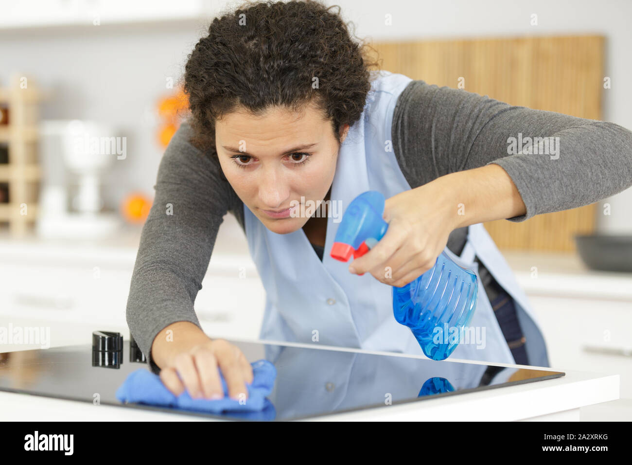 smiling housewife cleaning table surface in kitchen with spray Stock ...