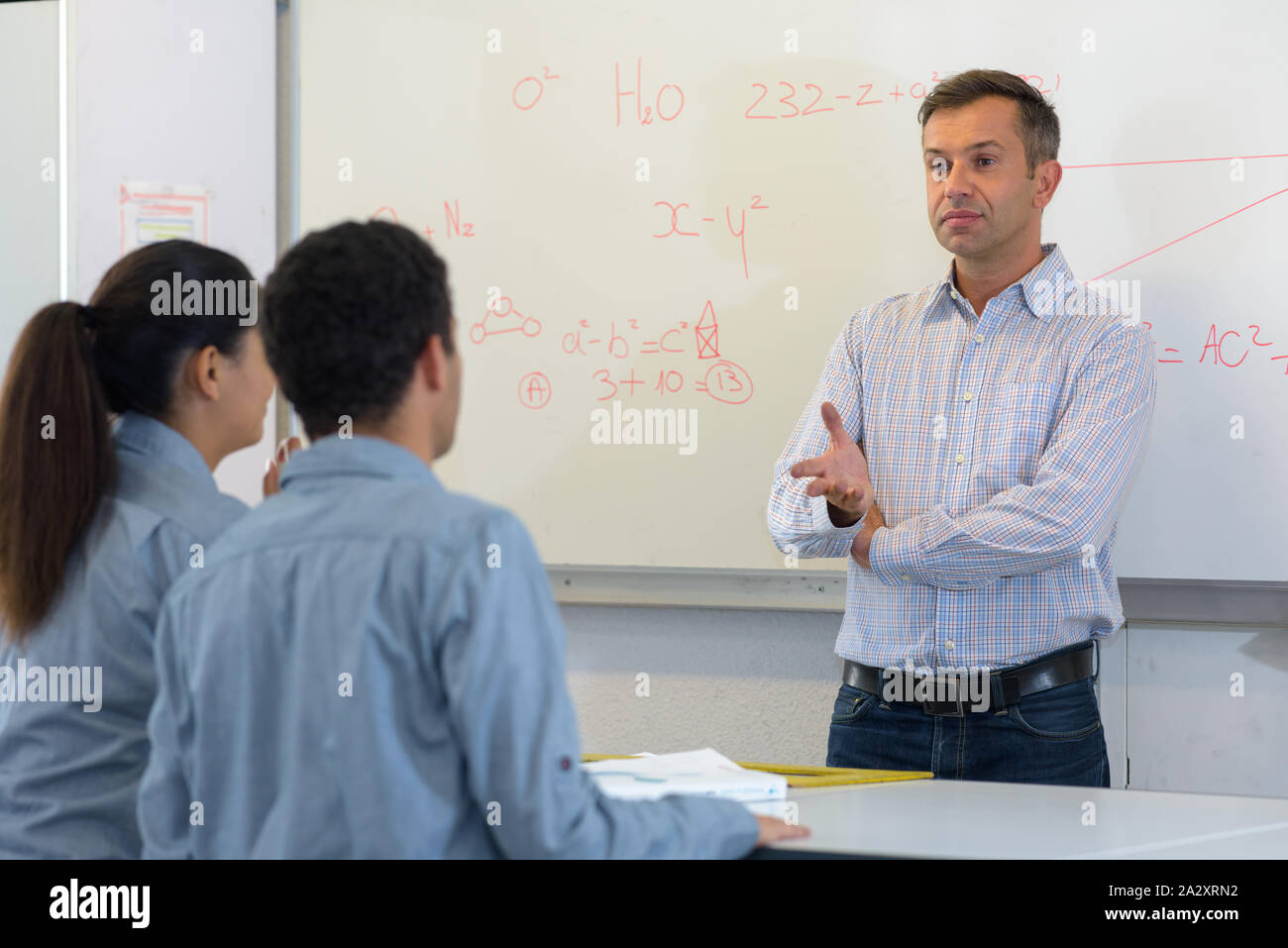 students and teacher with math formulas on white board Stock Photo - Alamy