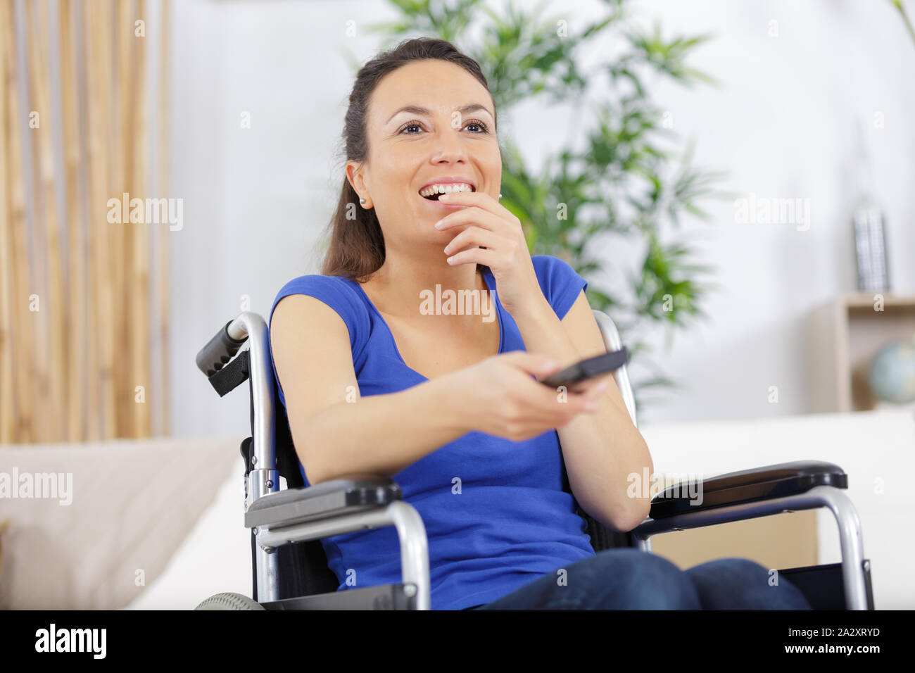 happy lady in wheelchair changing tv channel with remote control Stock ...