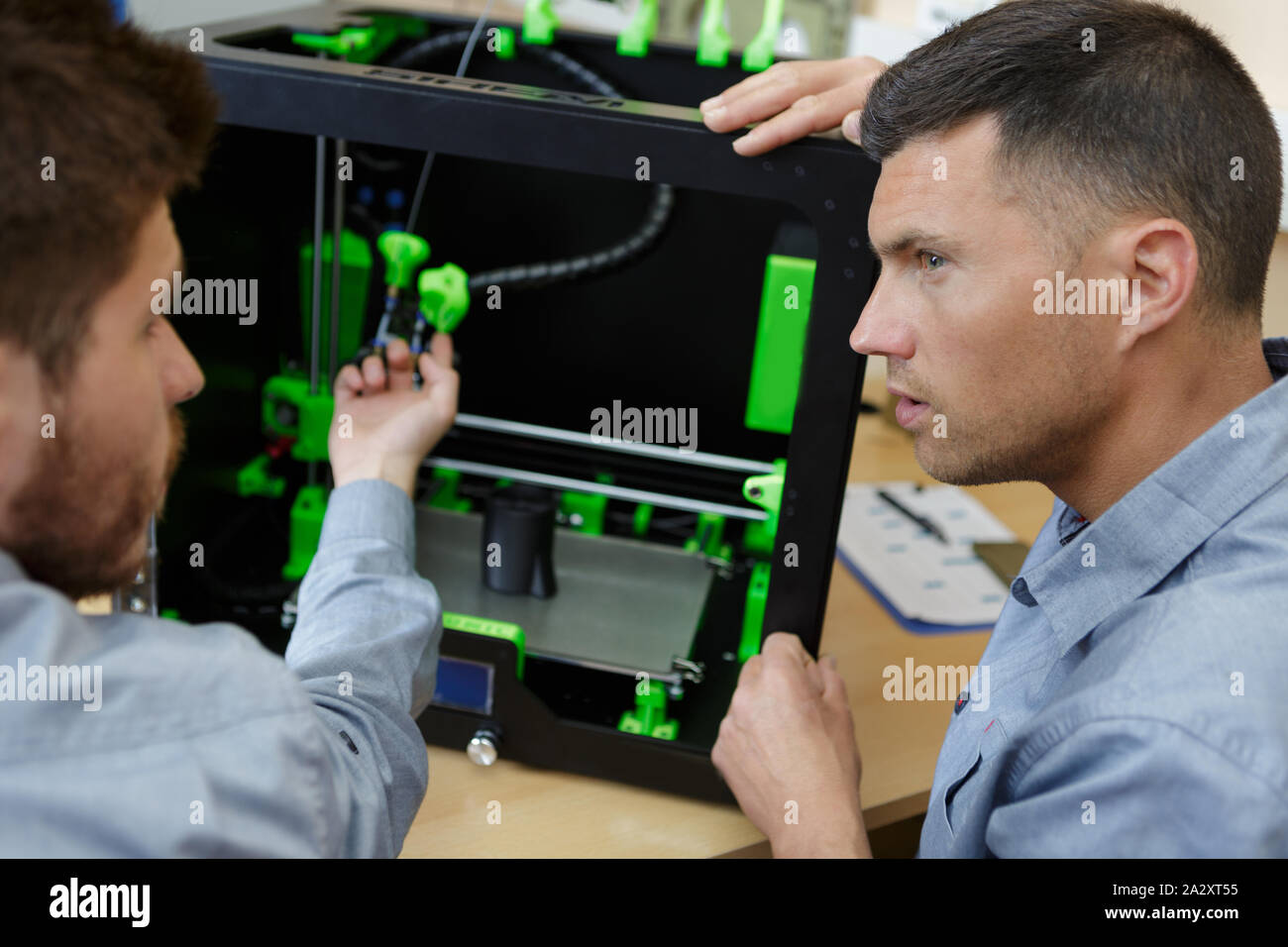 3d printer with two men looking at monitor screen Stock Photo - Alamy