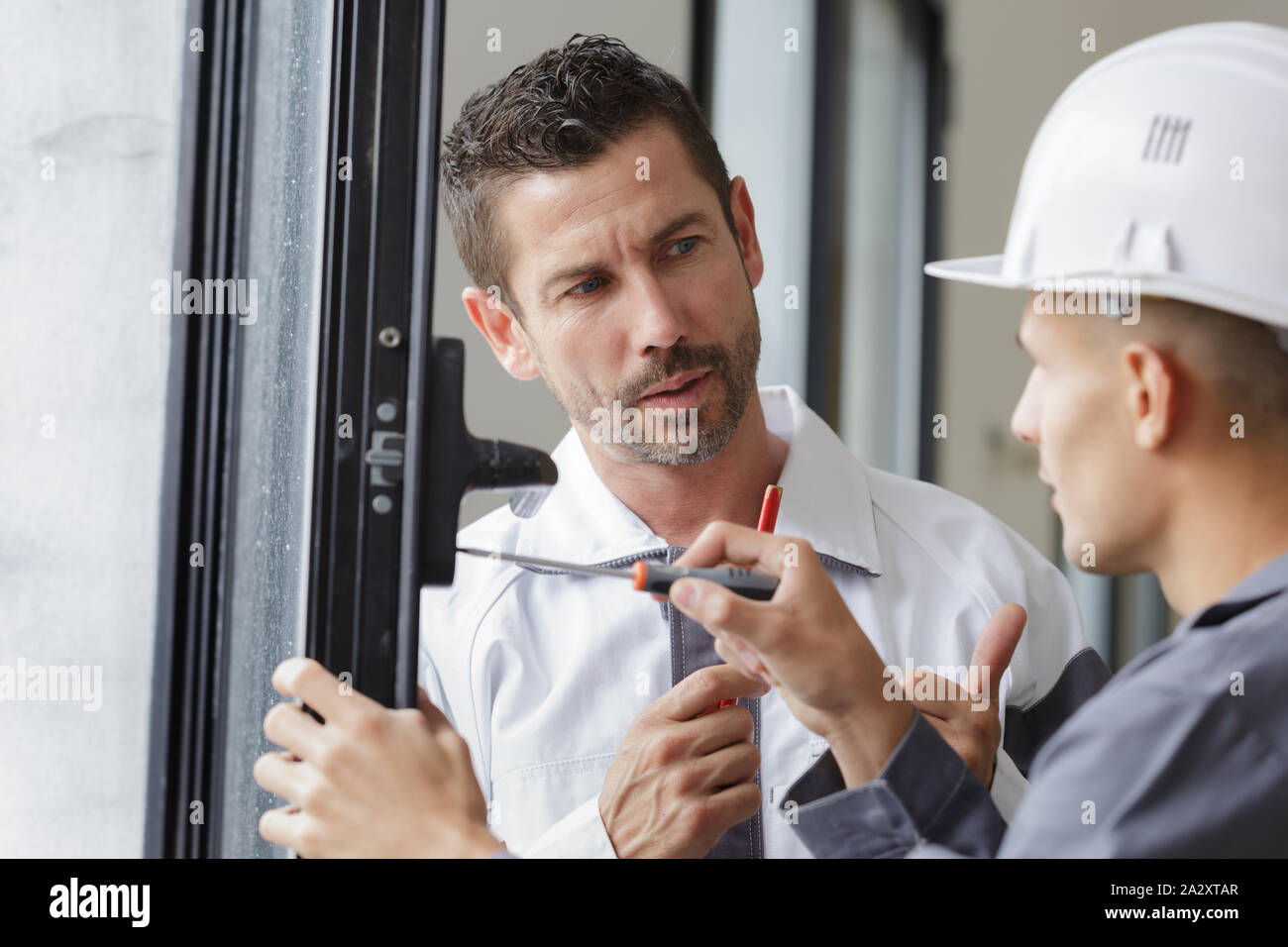 smiling man is fixing a window handle Stock Photo - Alamy