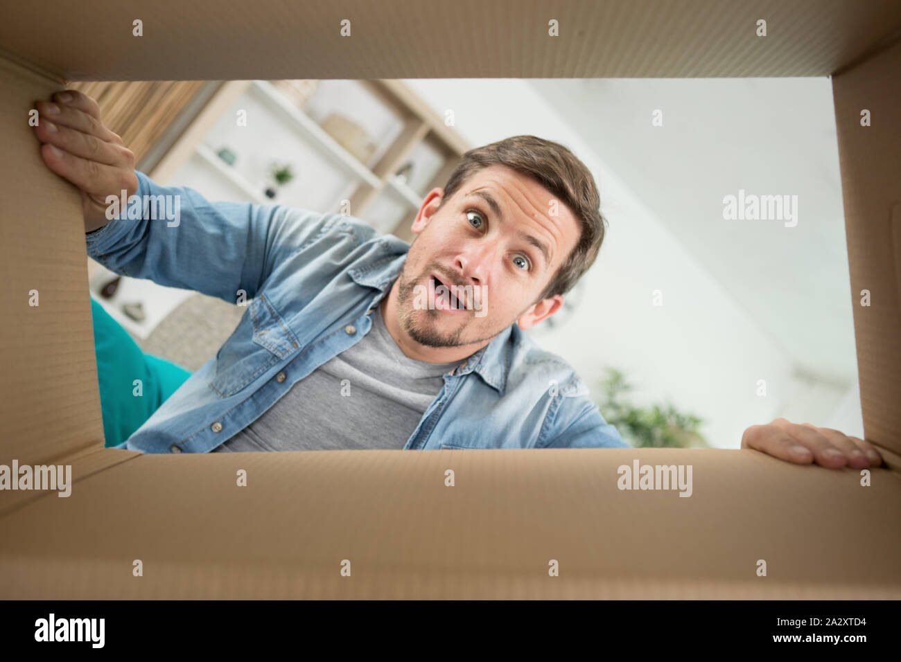 astonished man looking down into cardboard box Stock Photo - Alamy