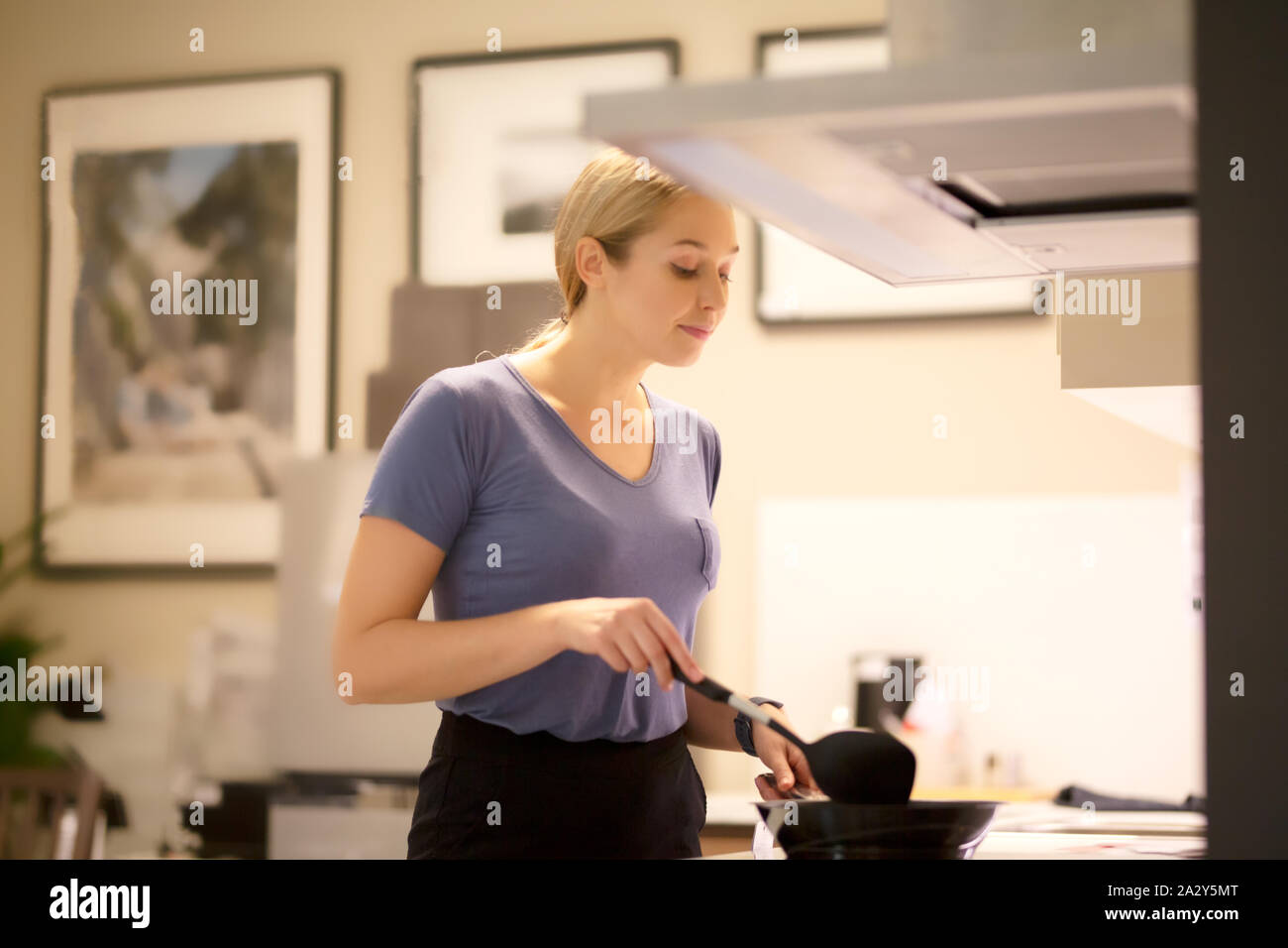 Side view portrait of women in her cooking dinner standing by stove and ...