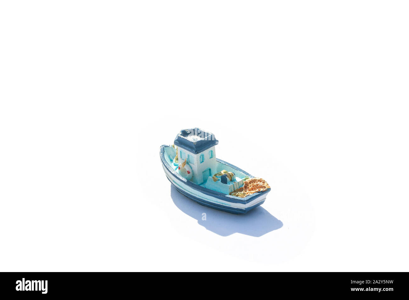 one blue miniature ship with shadow isolated on a white background ...