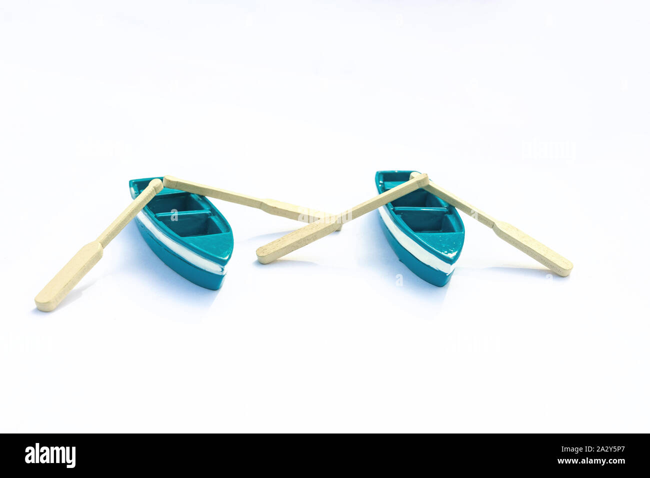 pair of blue miniature boats with oars isolated with shadow on a white ...
