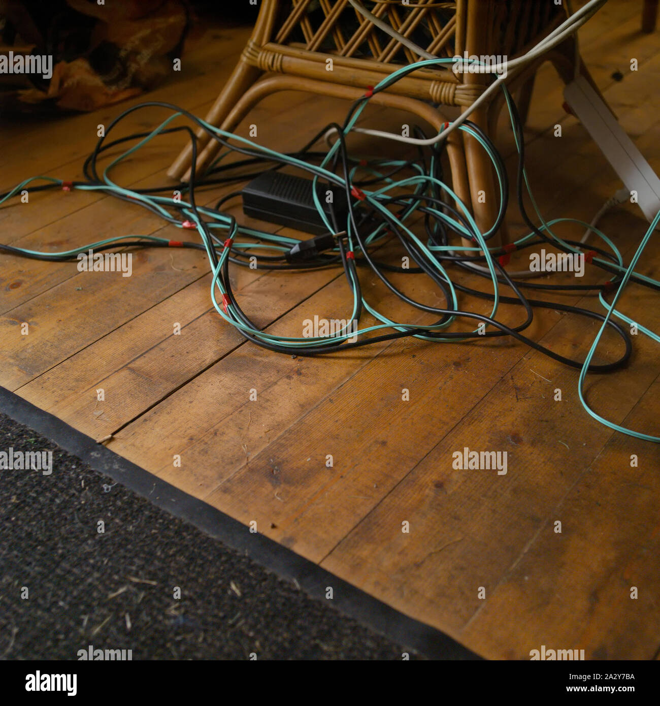 Tangled electric wires under a table indoor close-up Stock Photo - Alamy
