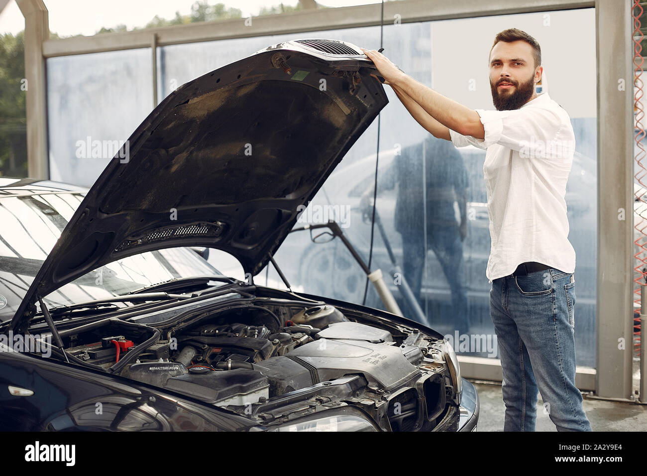 Man checks the engine. Guy checks his car Male in a white shirt Stock ...