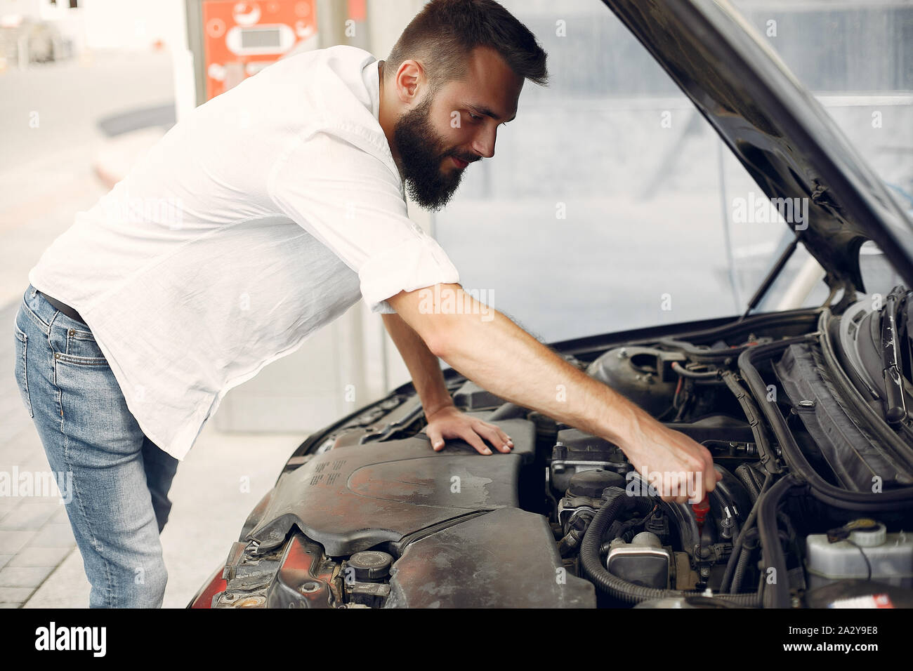Man checks the engine. Guy checks his car Male in a white shirt Stock ...
